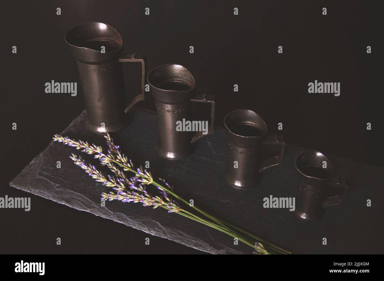 still life vintage measuring cups set on black rough stone board on ...