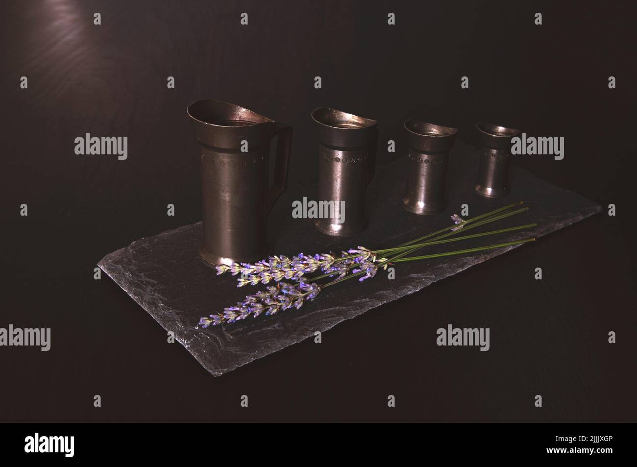 still life vintage measuring cups set on black rough stone board on ...