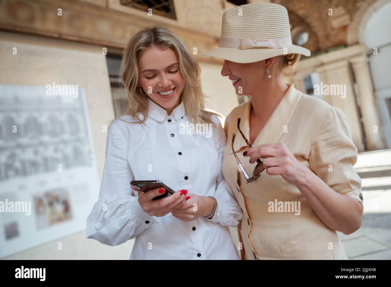 Smiling tourist standing beside a cheerful woman with the cellphone ...