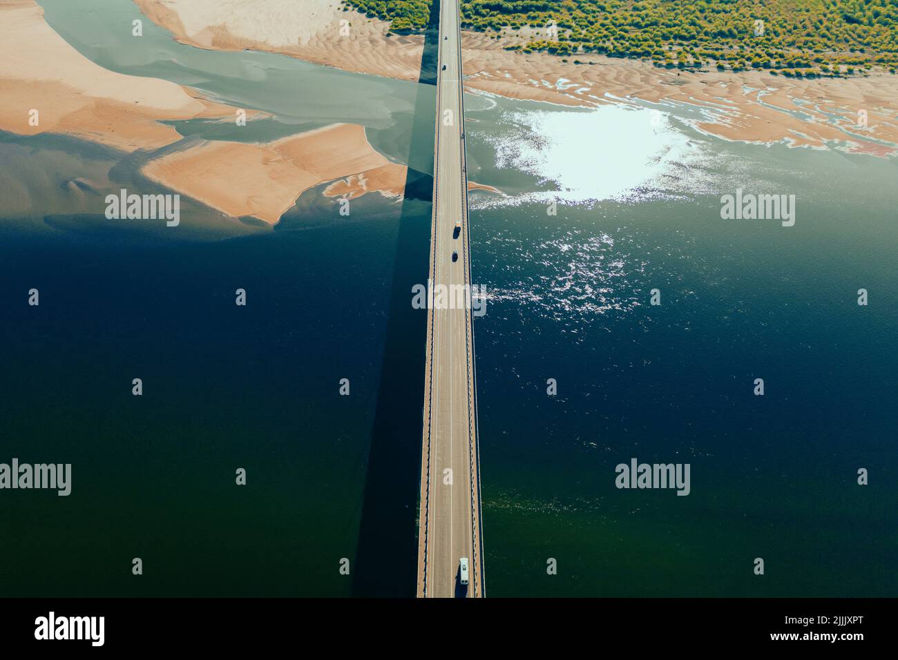 Aerial drone shot of cars driving on bridge over river and sandy ...