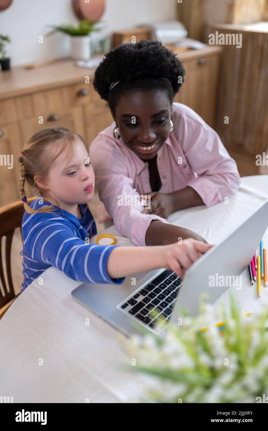 A girl with down syndrome sitting at the laptop with her tutor Stock ...