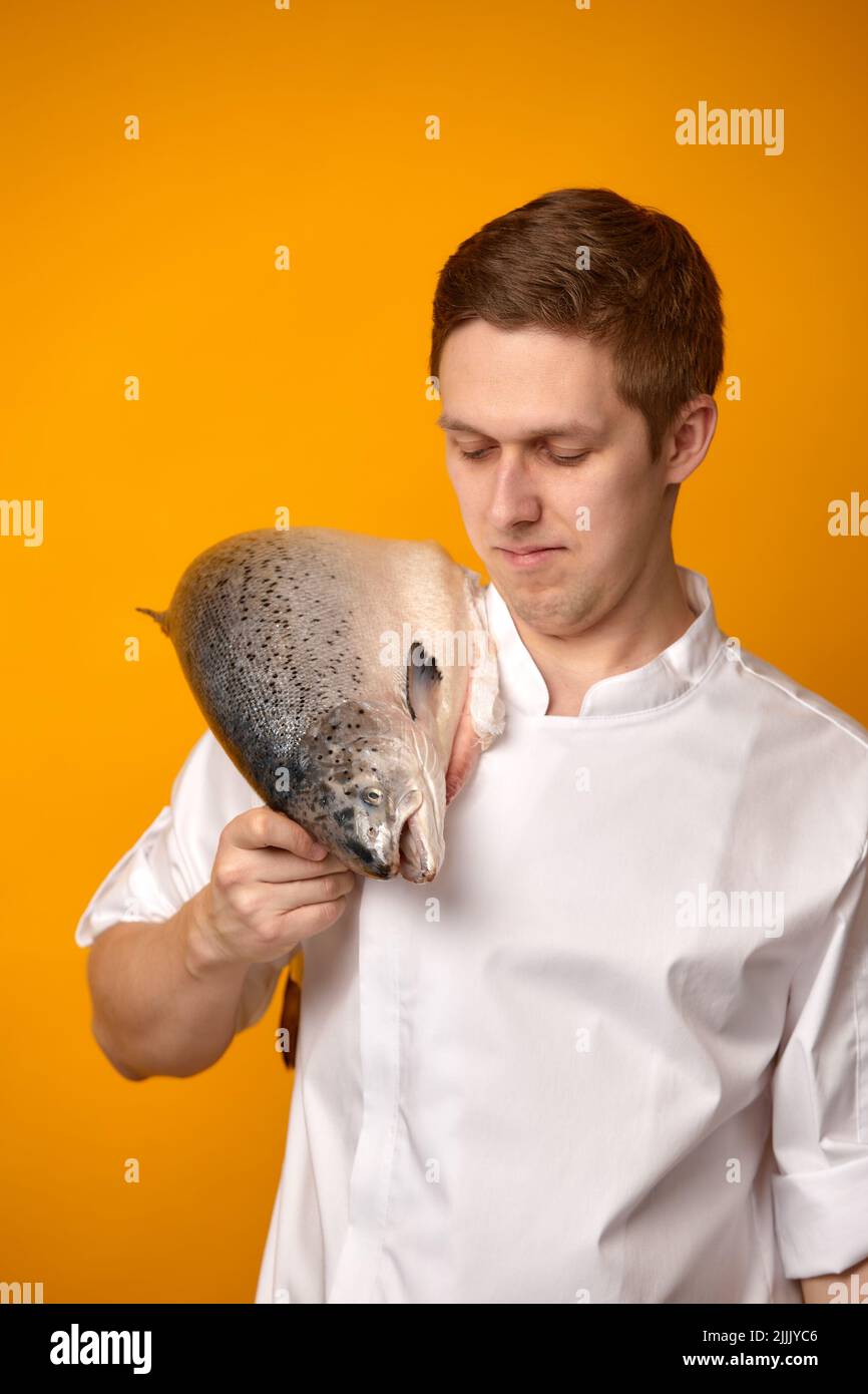 Chef cook holding a big atlantic salmon fish on his shoulder isolated ...