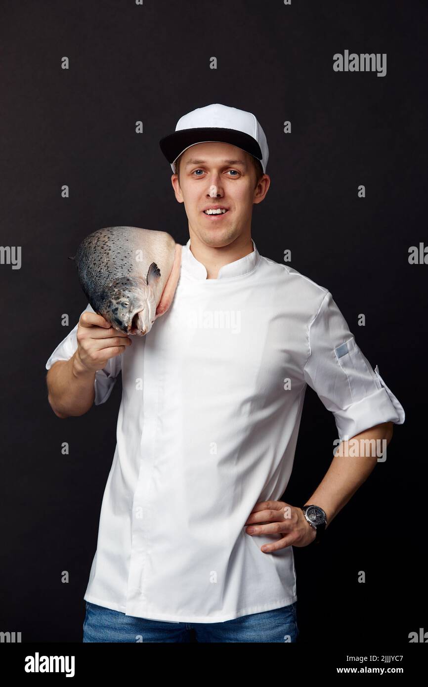 Chef cook holding a big atlantic salmon fish on his shoulder solated on ...