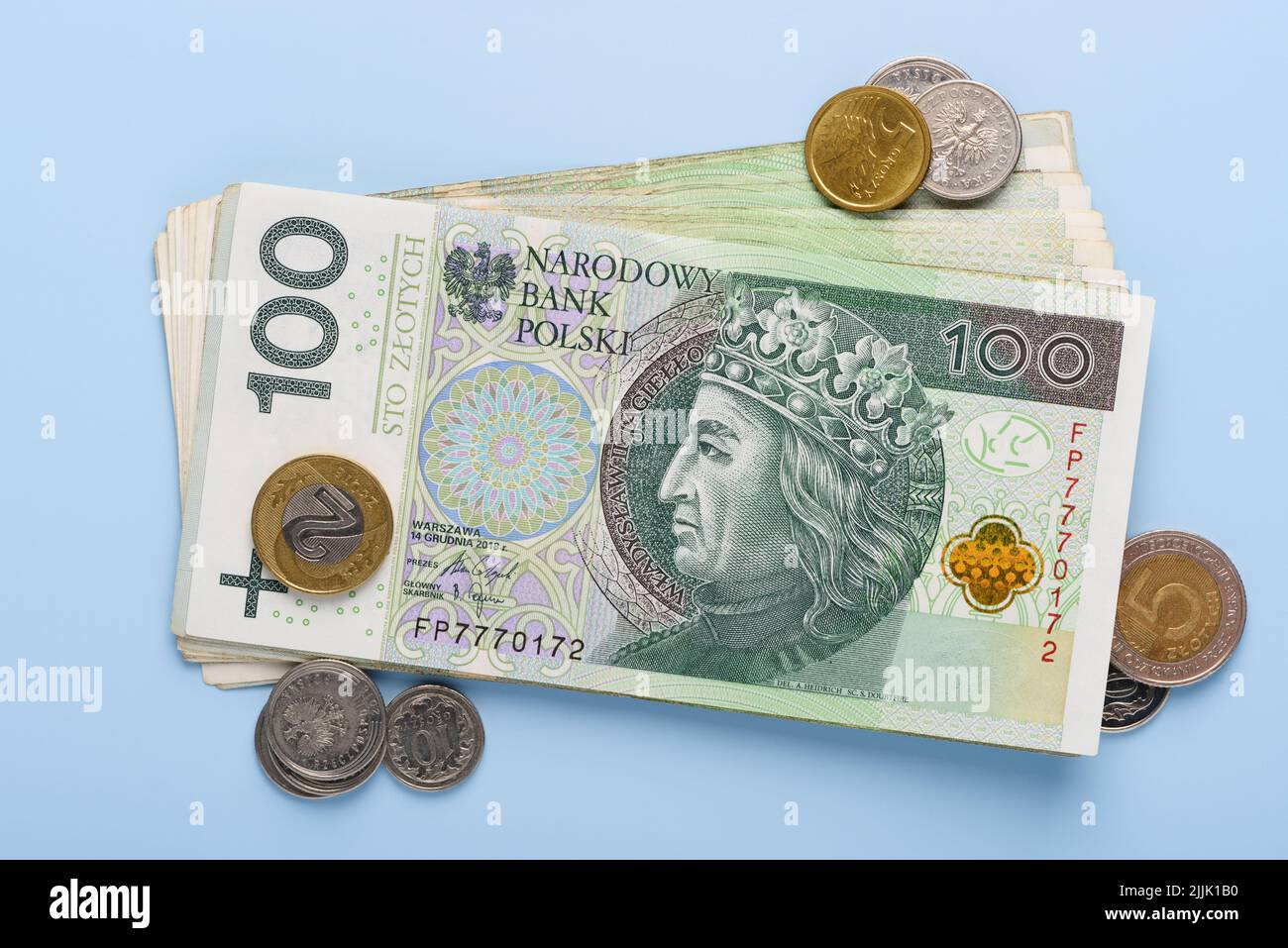 Stack of polish paper currency, 100 zloty PLN bills and coins, on blue ...