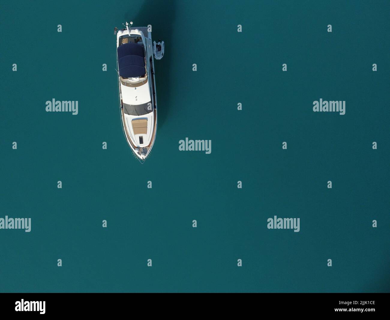 Aerial yacht on calm sea. Luxury cruise trip. View from above of white boat on deep blue water ...