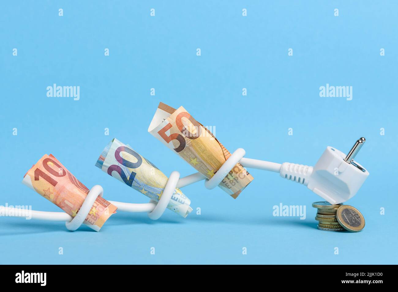 Euro bills tied in knots in electrical power cable with plug on coins ...