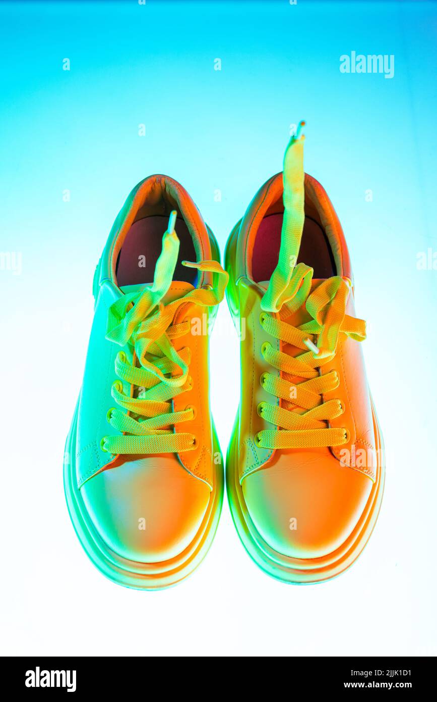 Aerial view of sports shoes, sneakers isolated over neoned background ...