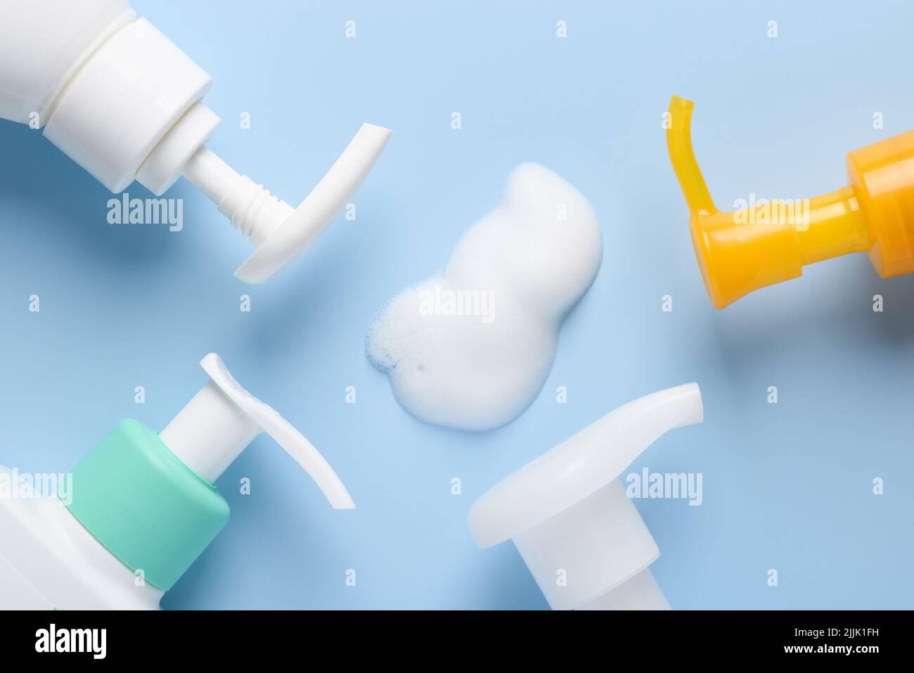 Skin care cosmetic bottles with pump dispenser and foam smear on blue ...