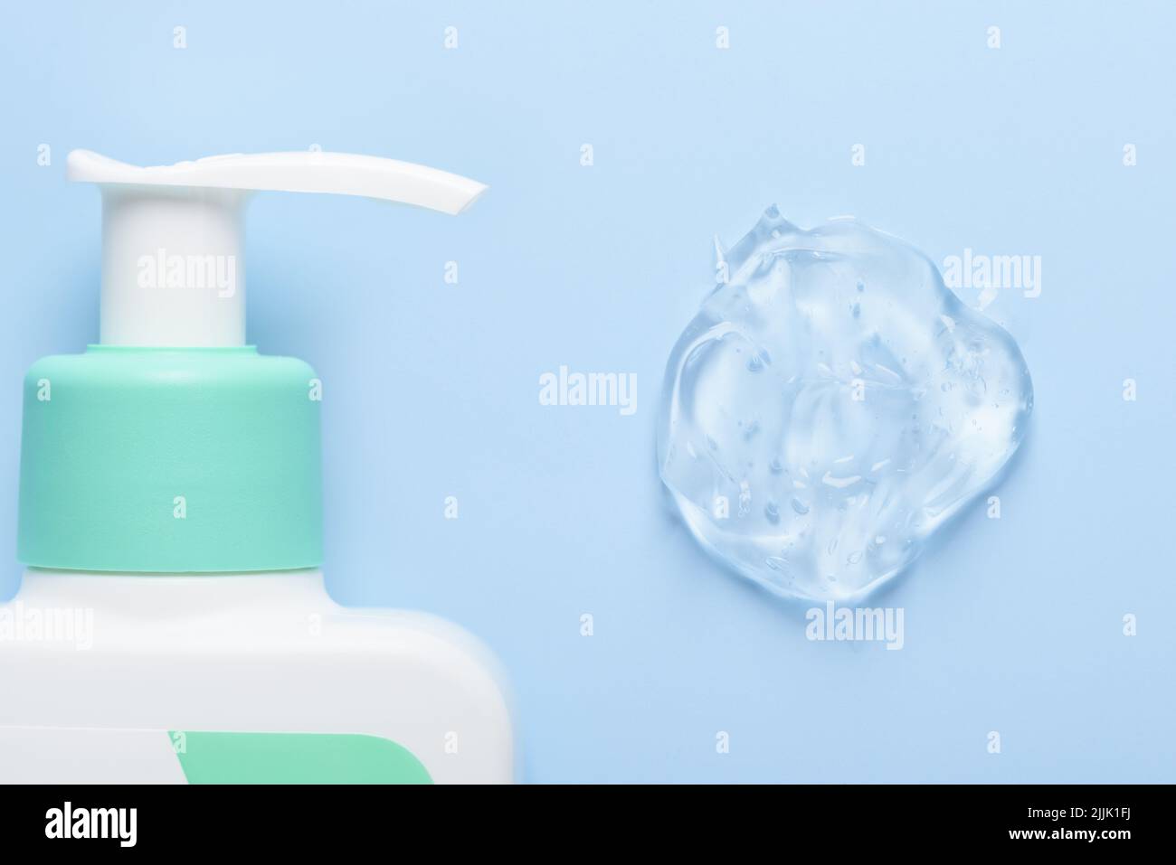 Cosmetic bottle with pump dispenser and transparent gel smear on blue ...