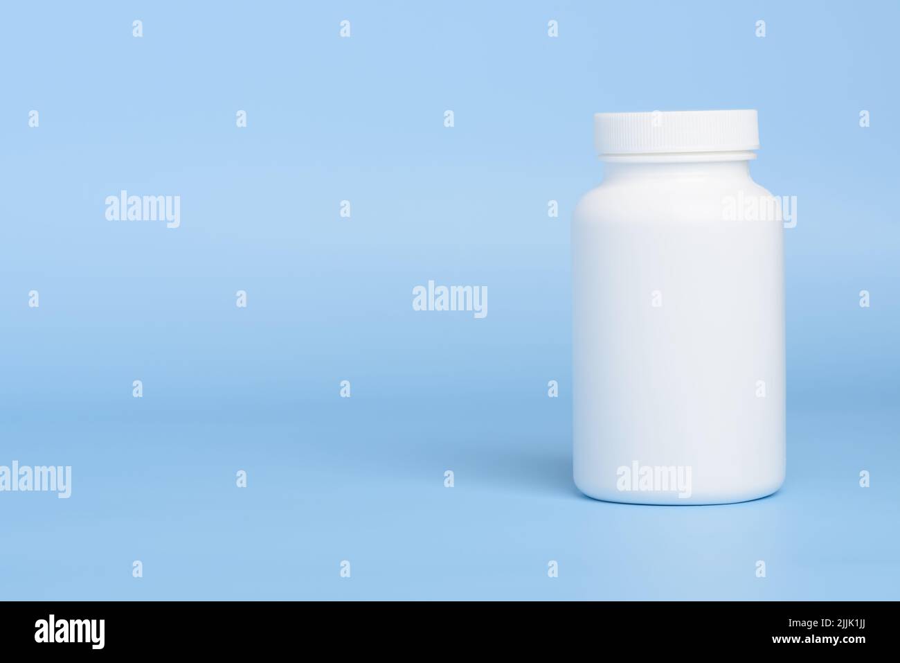 One white blank plastic medical pill or supplement bottle on blue ...