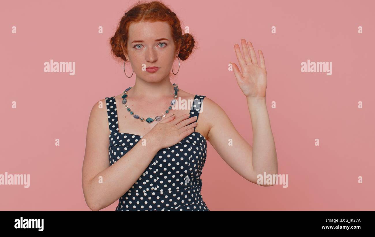 I swear to be honest. Sincere responsible redhead woman raising hand to ...