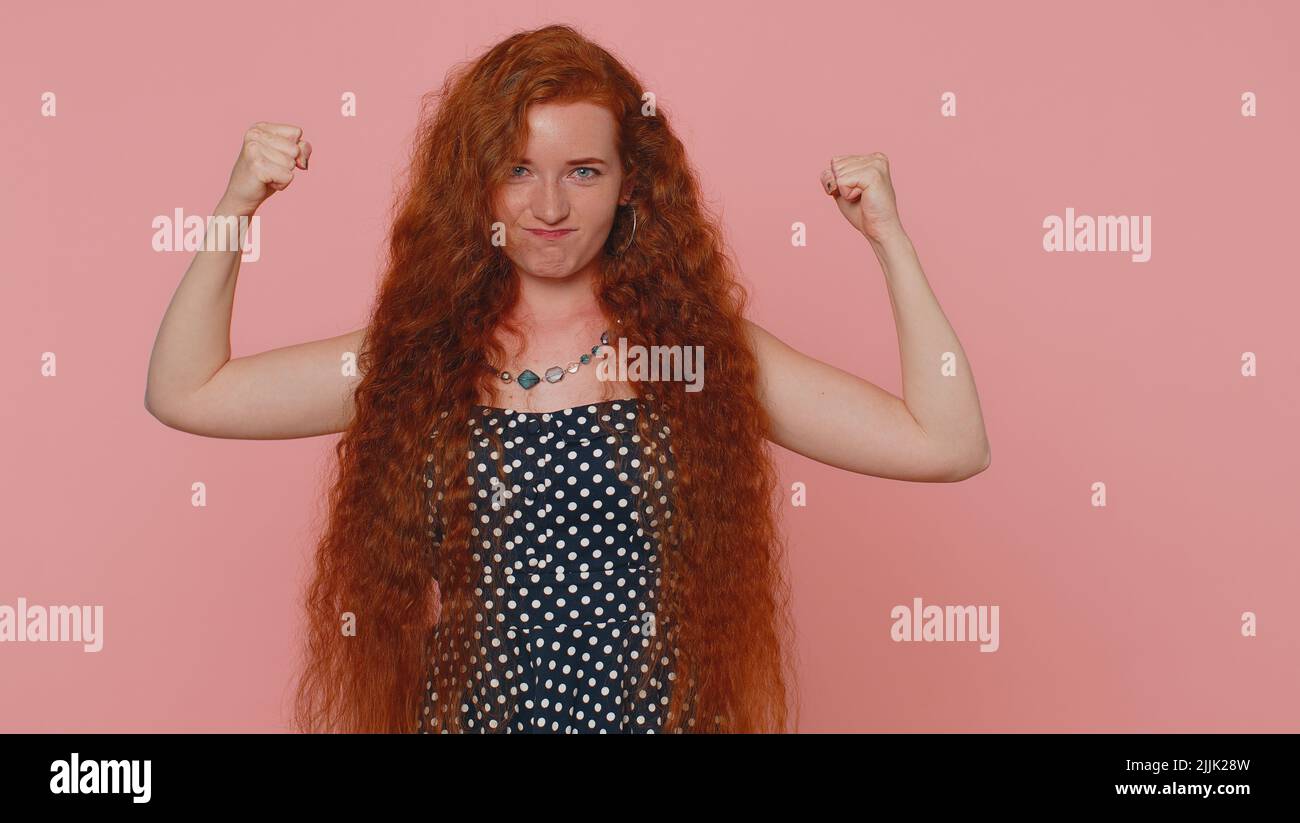 I am strong and independent. Young redhead woman showing biceps and ...