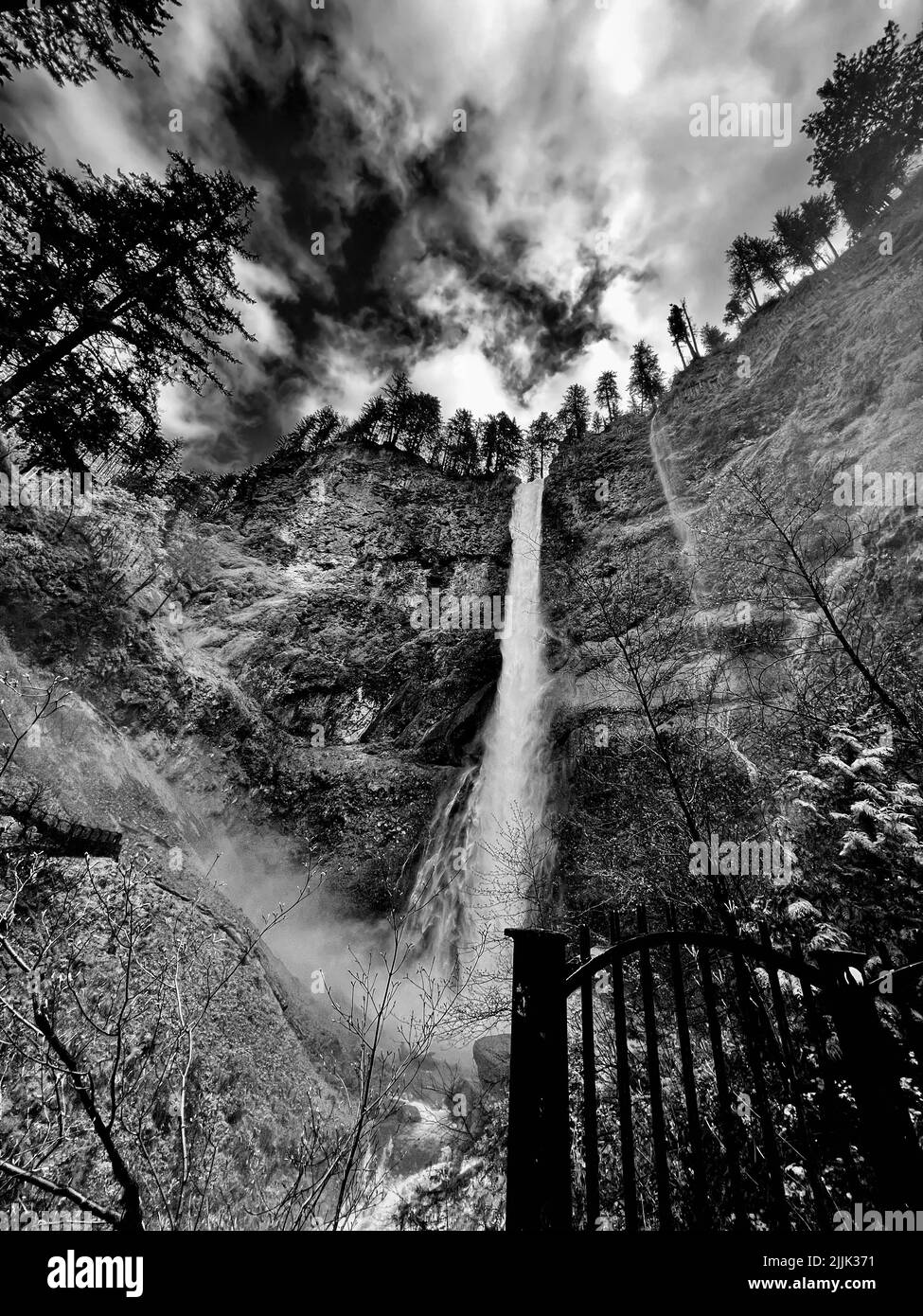 A low angle of a waterfall flowing down the rocks covered with trees ...