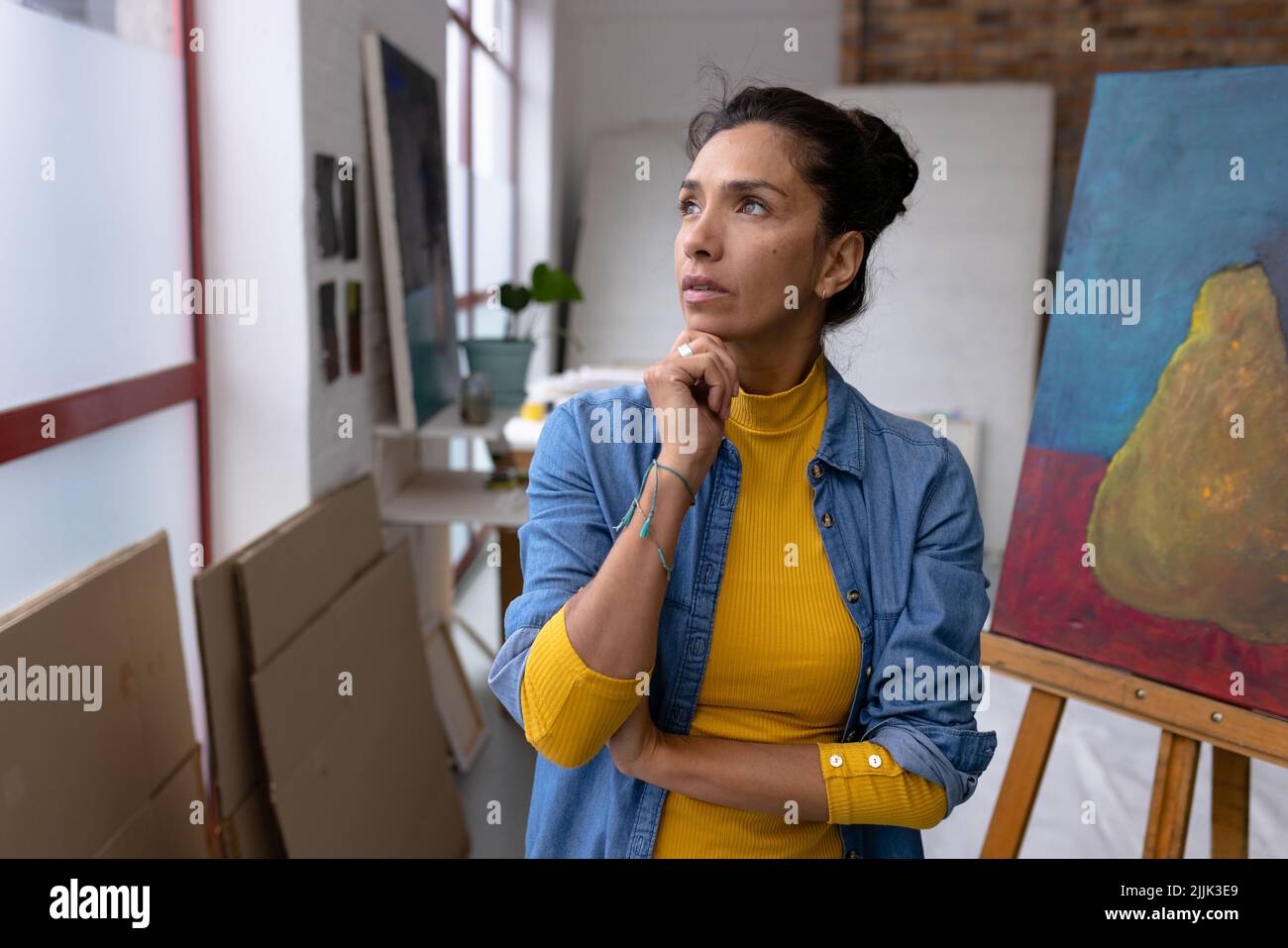 Image of thoughtful biracial female artist working on new painting in ...