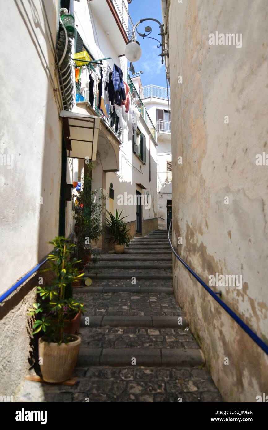 A vertical shot of a long and narrow street with stairs, balconies with ...