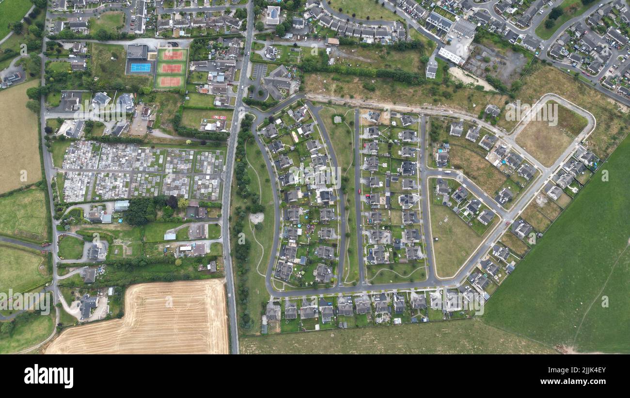 A birds eye view shot of a small town surrounded by green and brown ...