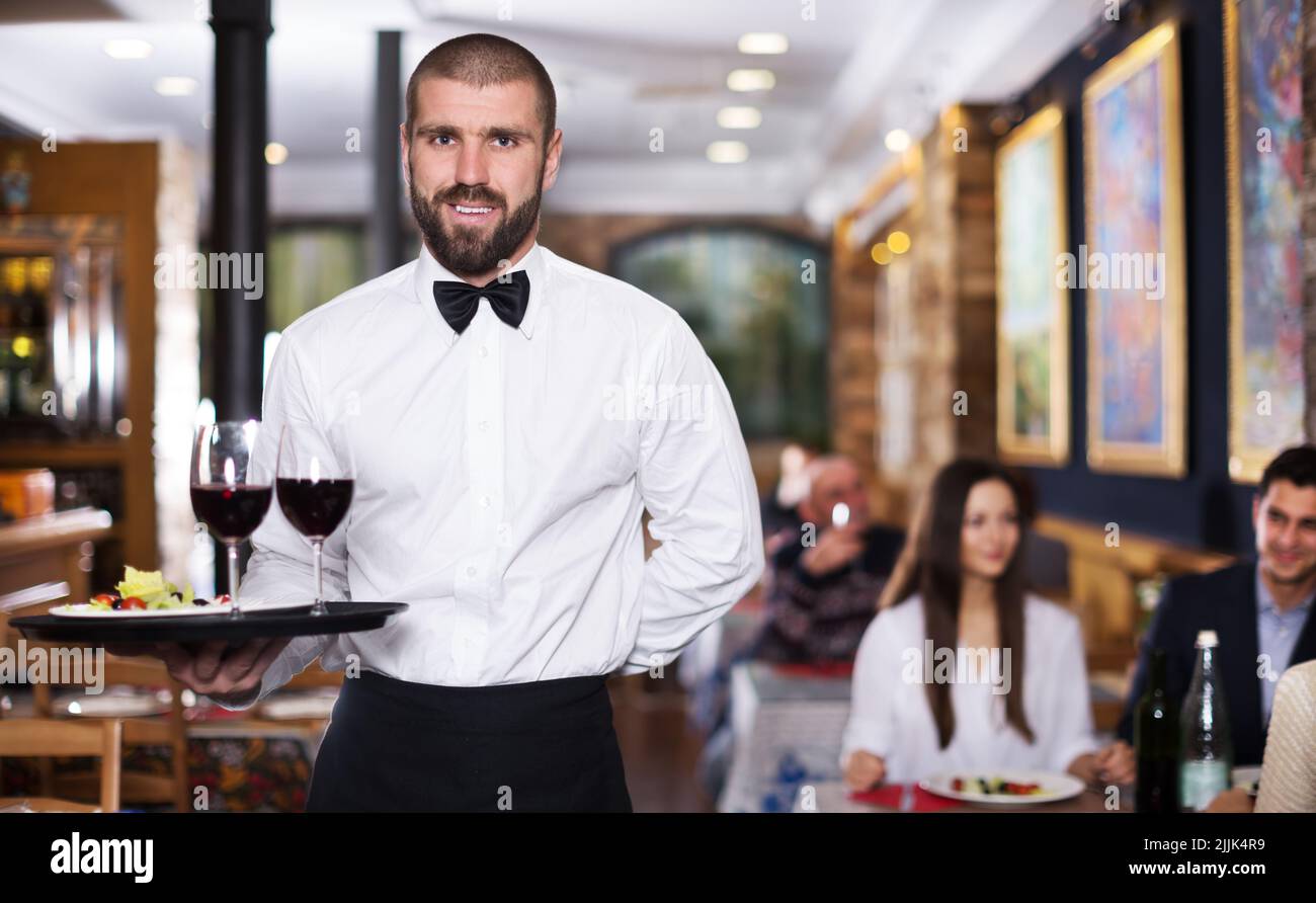 Smiling waiter with serving tray in restaurant Stock Photo - Alamy