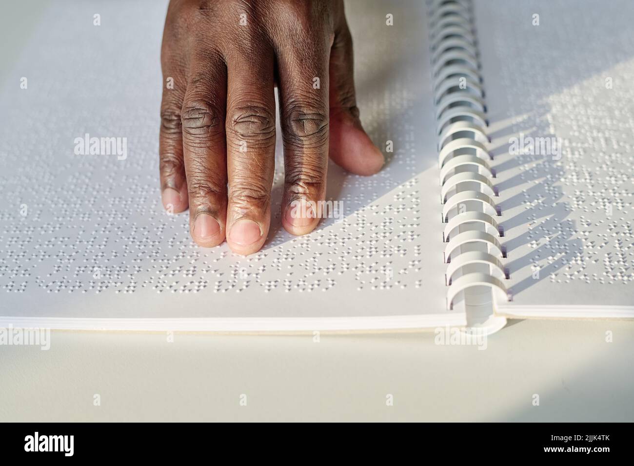 Close-up of African senior blind man reading text in braille language ...