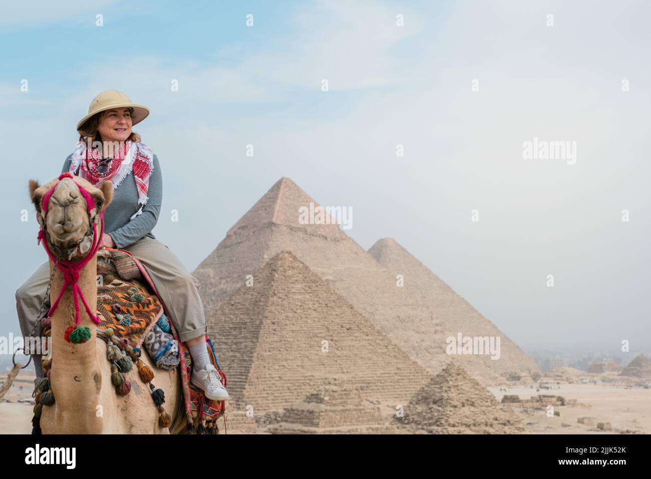 tourist woman riding a dromedary in front of pyramids. Egypt, Cairo ...