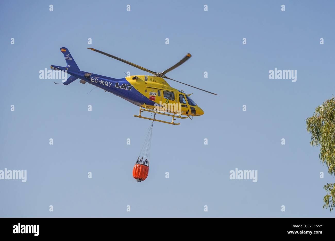 Helicopter of INFOCA carrying a water bucket to drop on a wildfire ...