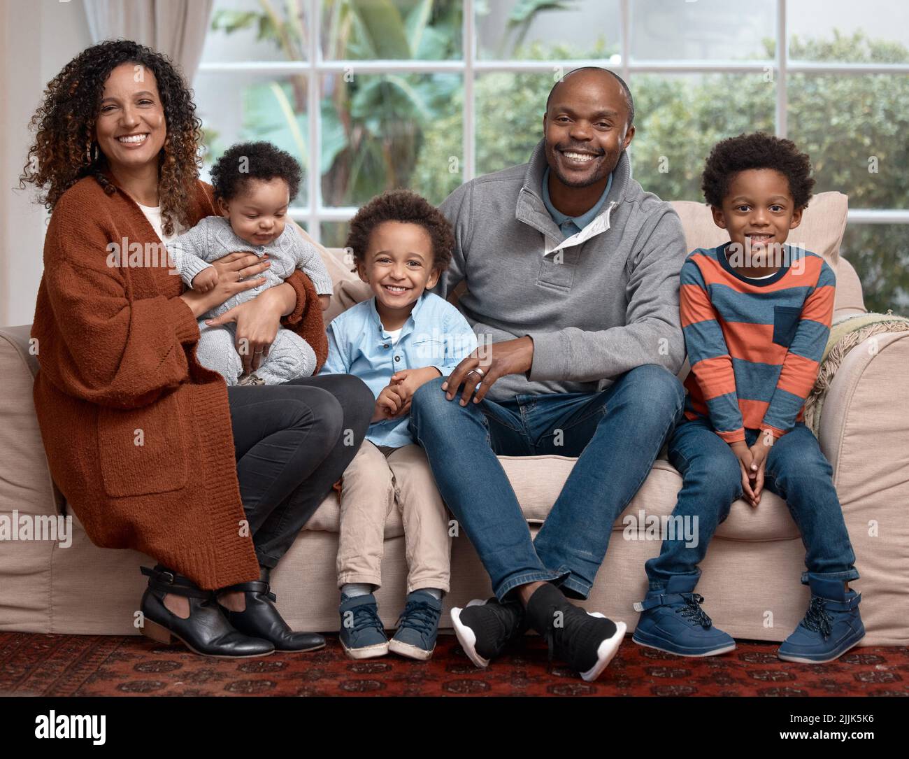 They keep us busy but we love it. Portrait of a happy family relaxing on a sofa at home Stock ...