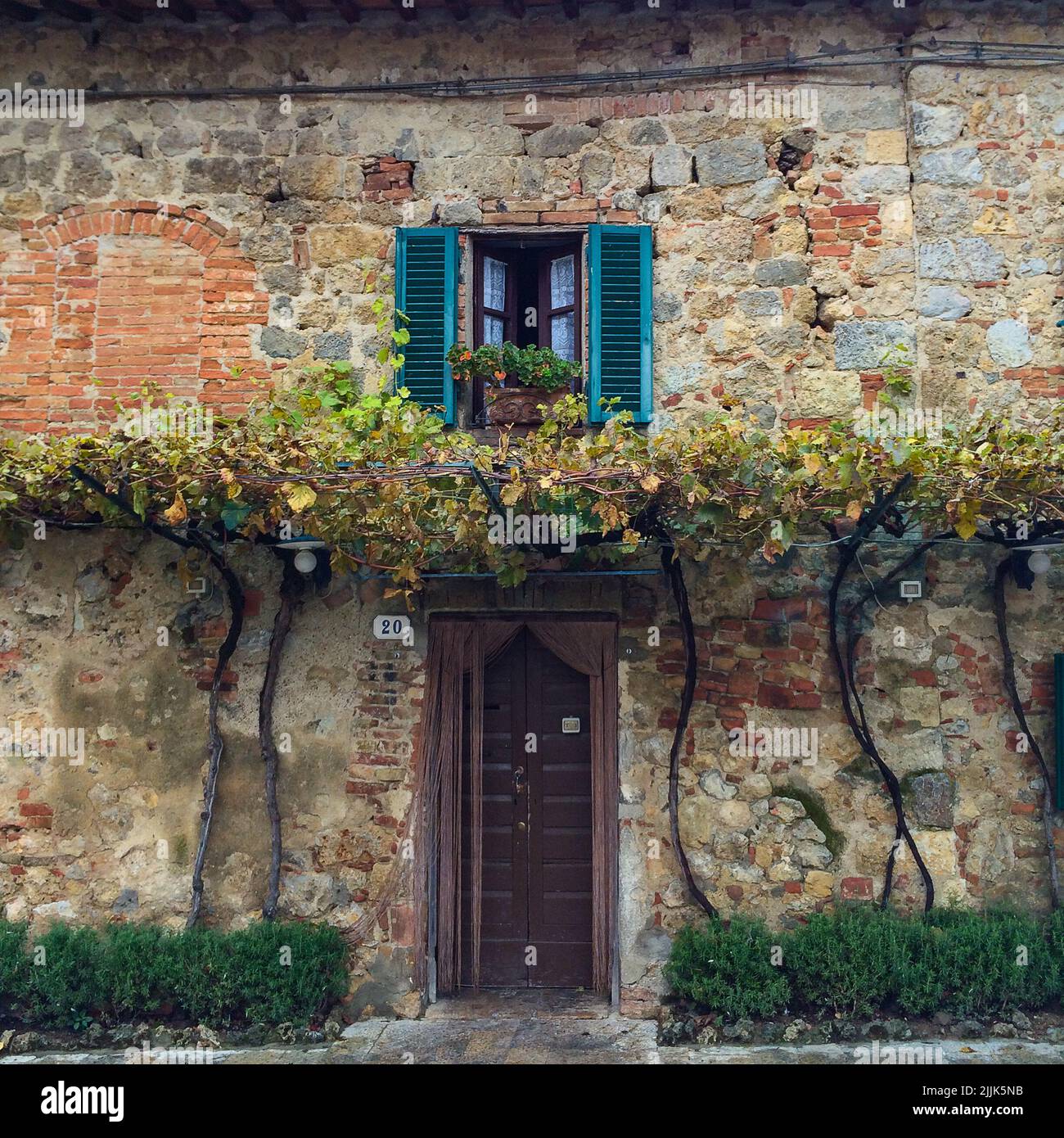 A Tuscan house from bricks and blue window blinds in town Monteriggioni ...