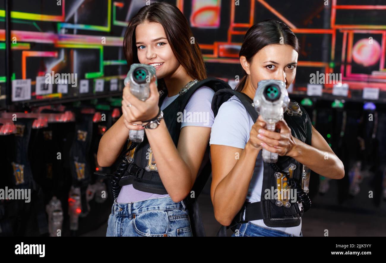 Girl took aim and holding guns during laser tag game in dark labyrinth ...