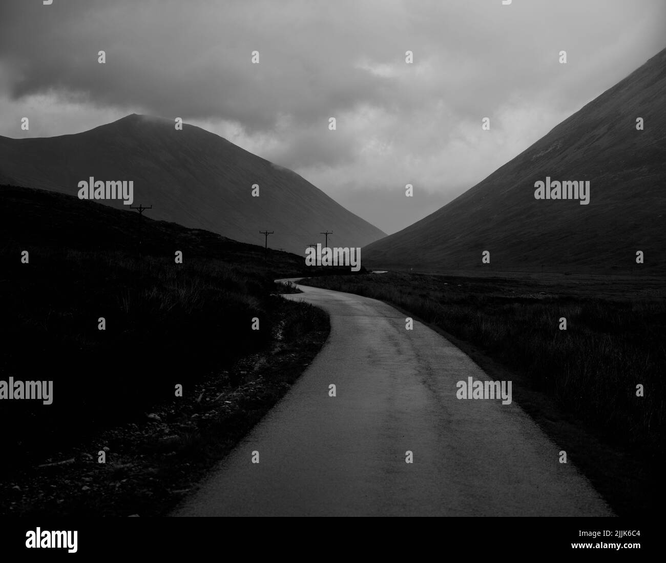 Low clouds and rain over a mountain road in the remote empty landscape ...