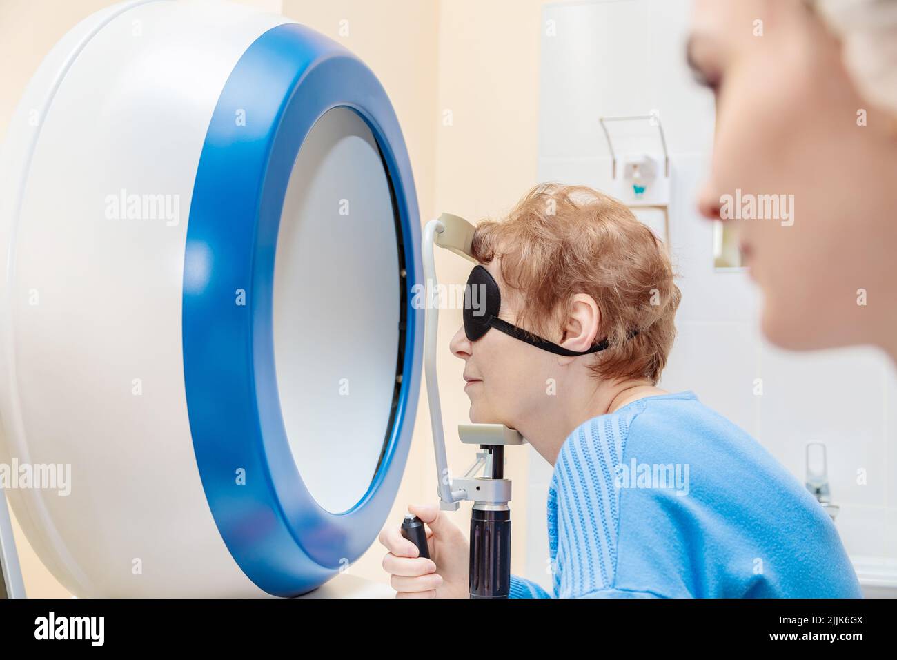 A girl optometrist examines the eyes of a patient using special modern ...
