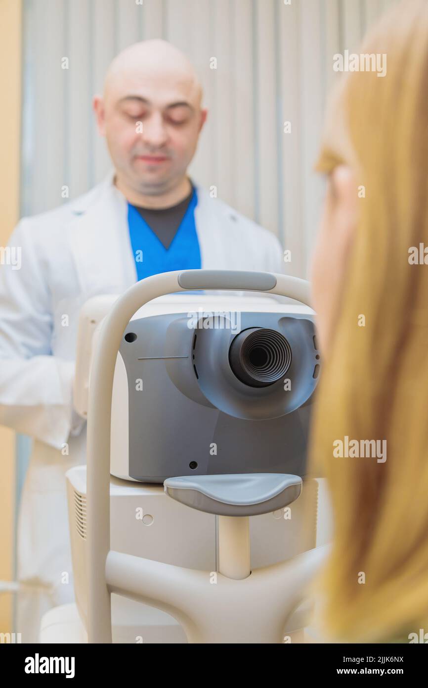 A male ophthalmologist checks the eyesight of a young girl using a ...