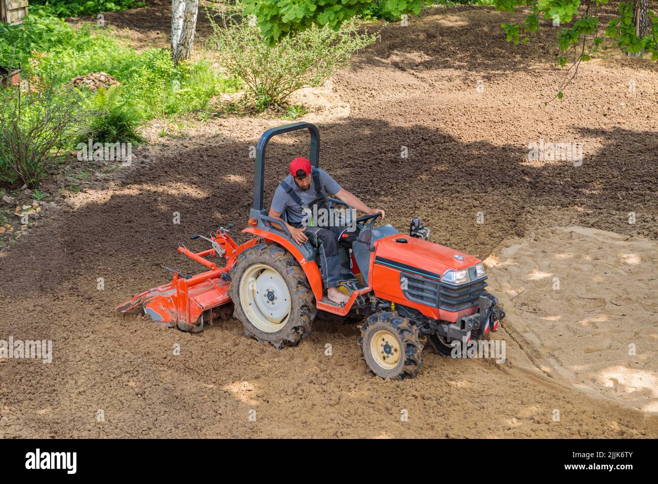 A farmer on a mini tractor loosens the soil for the lawn. Land ...