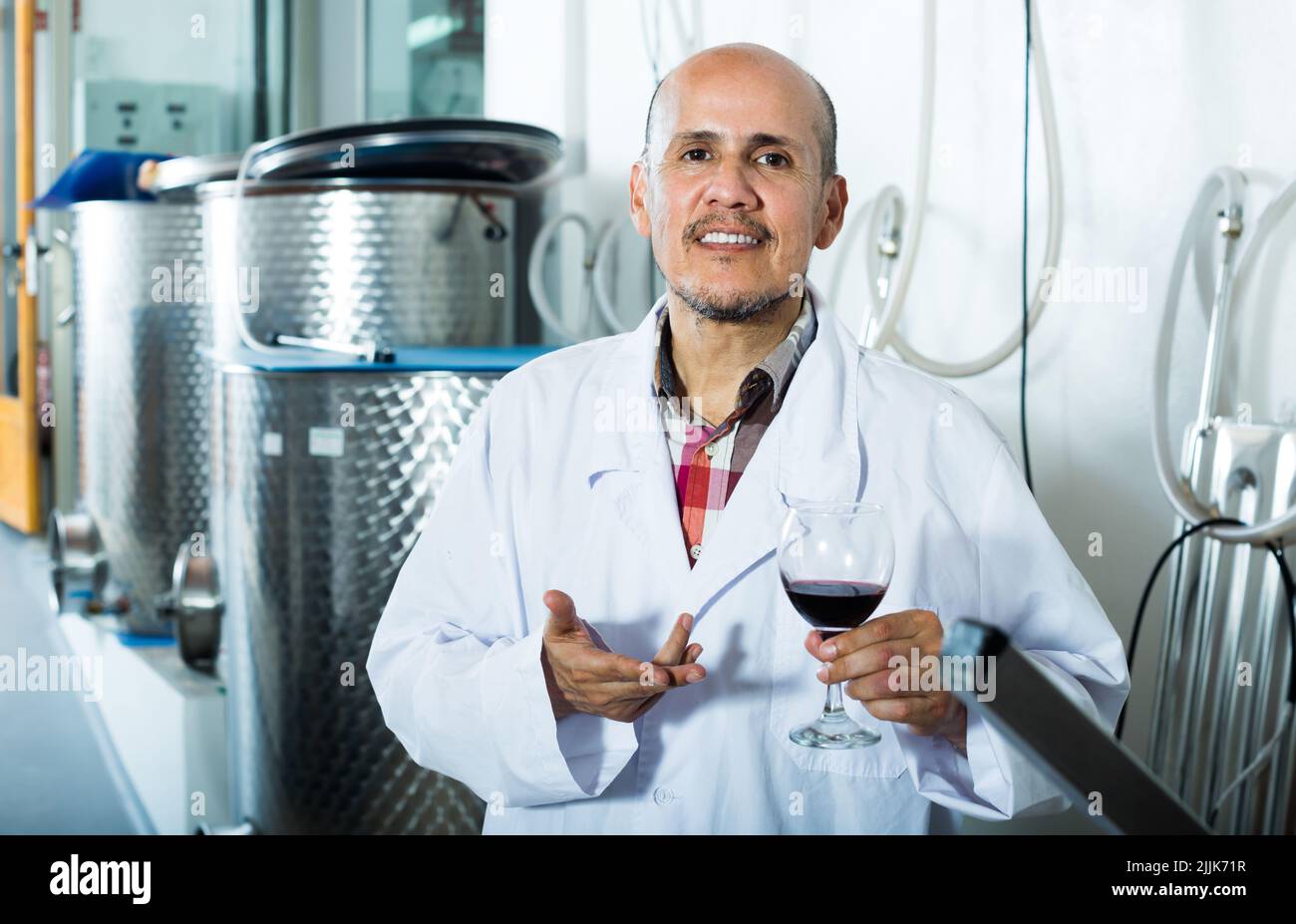 Smiling winery worker holding glass of wine Stock Photo - Alamy
