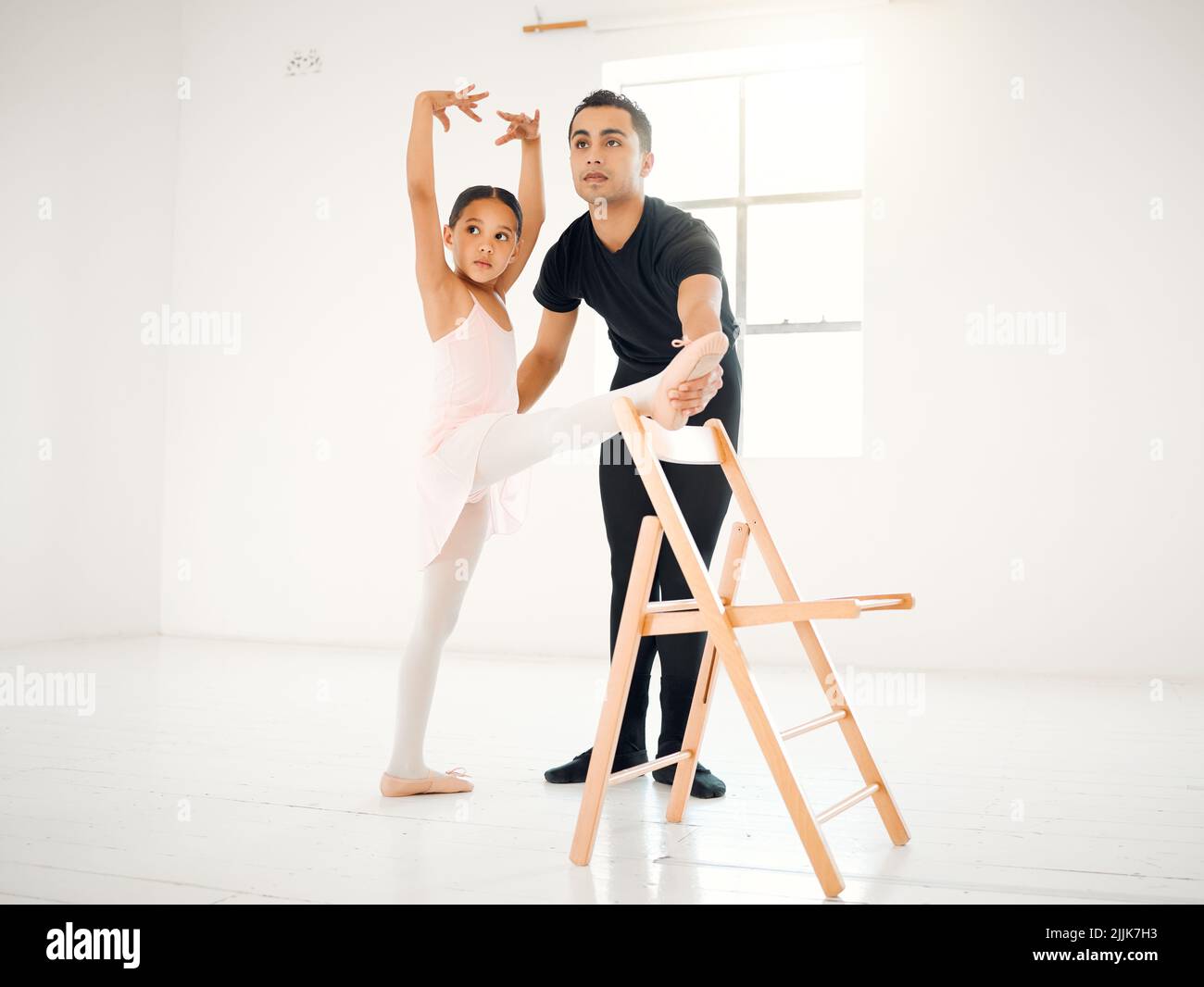 Ballet builds confidence and self esteem. a ballet teacher assisting a ...