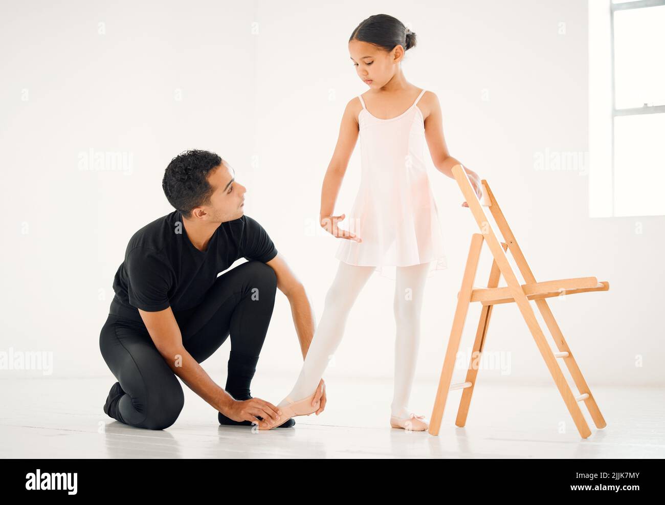 Hold onto the chair for some balance. a ballet teacher assisting a ...