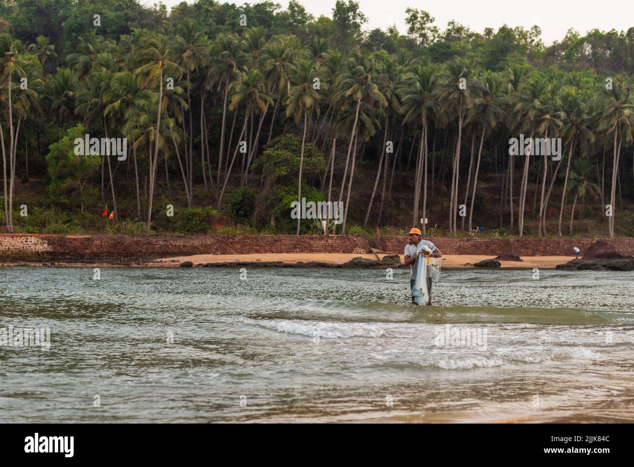A local Indian fisherman throwing the net into the ocean in the village ...