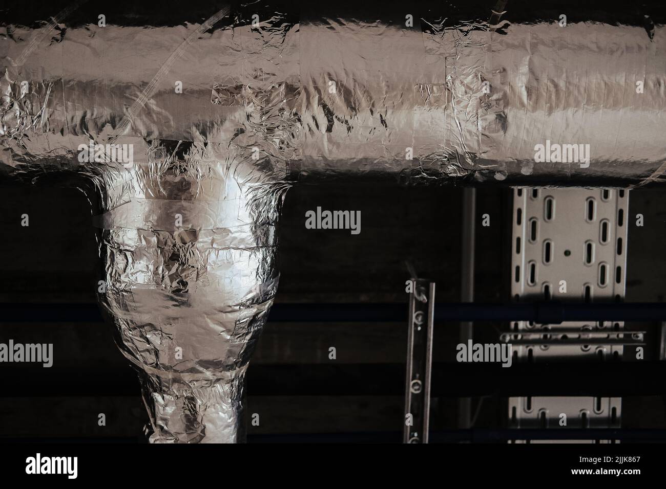 A silver color pipe in the dark room with the window in background ...