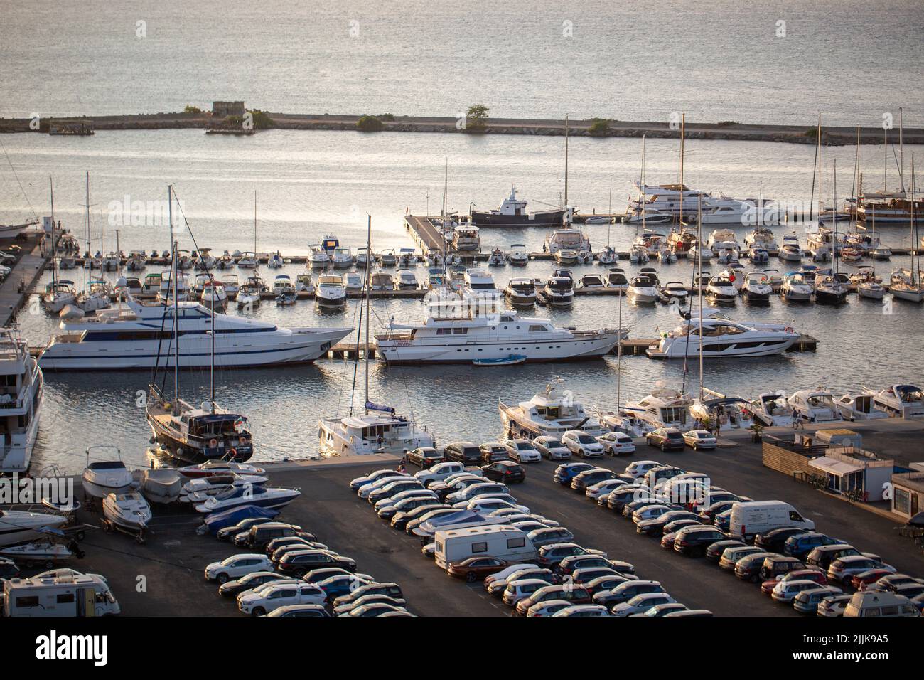 A beautiful shot of a harbor full of boats and a parking full of cars ...