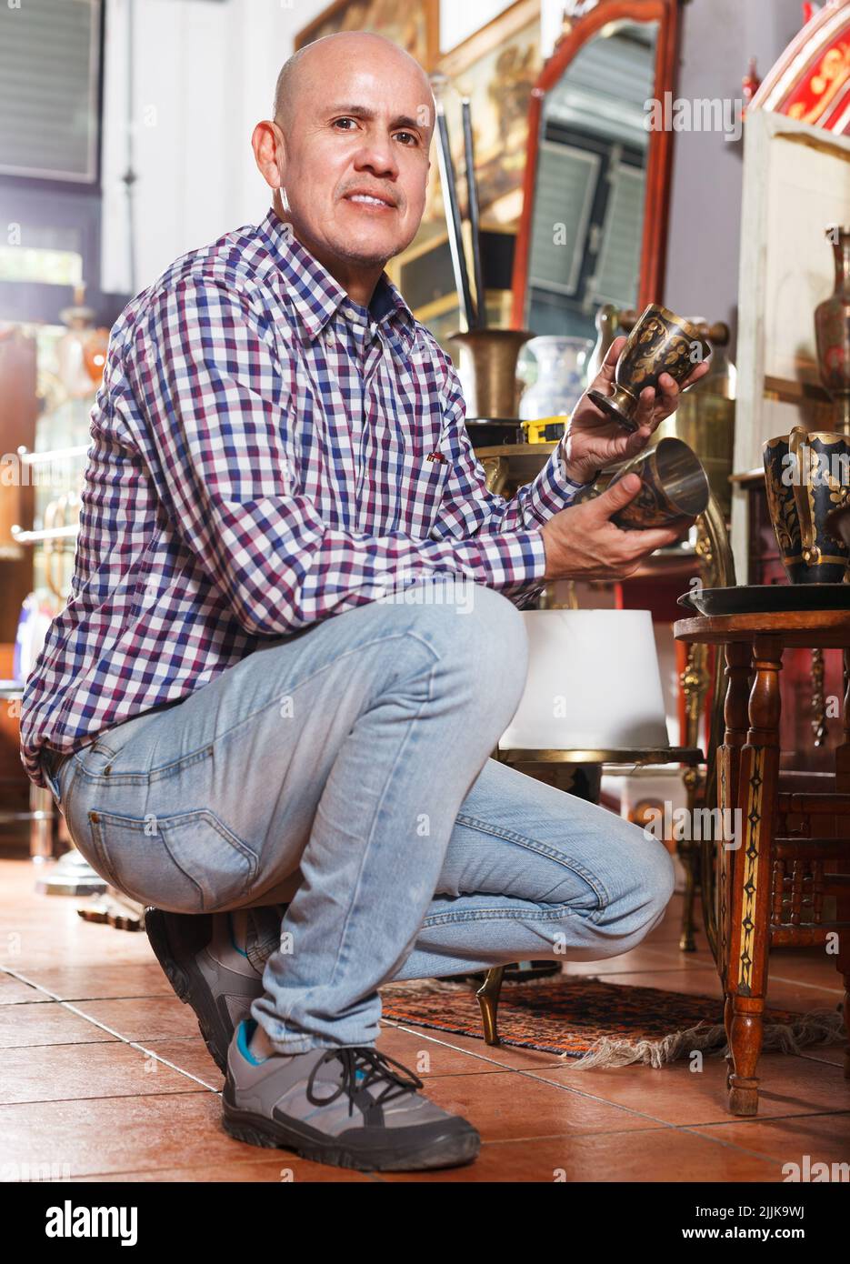Man choosing ancient things in store Stock Photo - Alamy