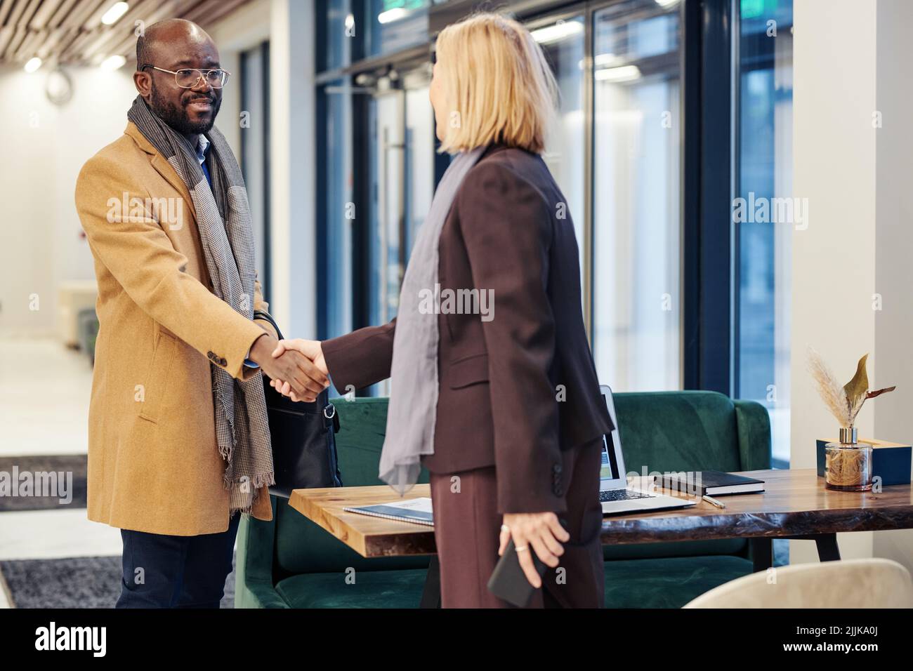 Two lawyers greeting and smiling to each other while having a business ...