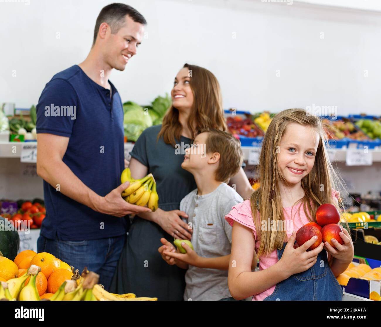 Smiling preteen girl looking for fresh delicious nectarine during ...