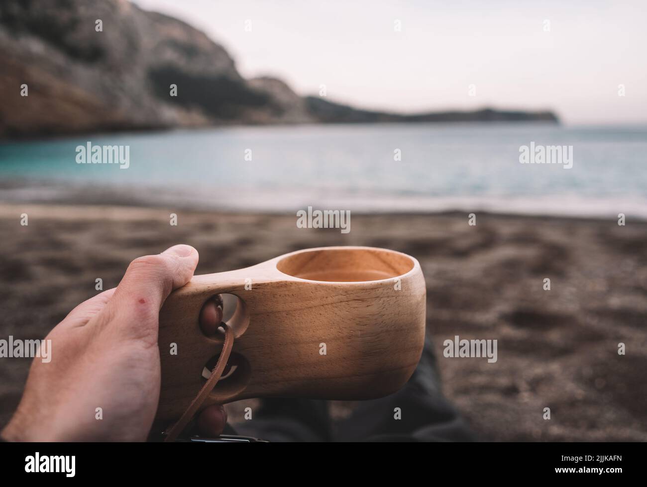 A beautiful wooden cup of tea in someone's hand sitting on beach Stock ...