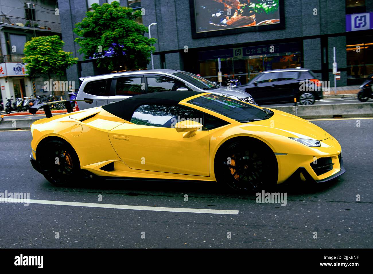A yellow Lamborghini fast sports car driving in the streets of Taipei ...