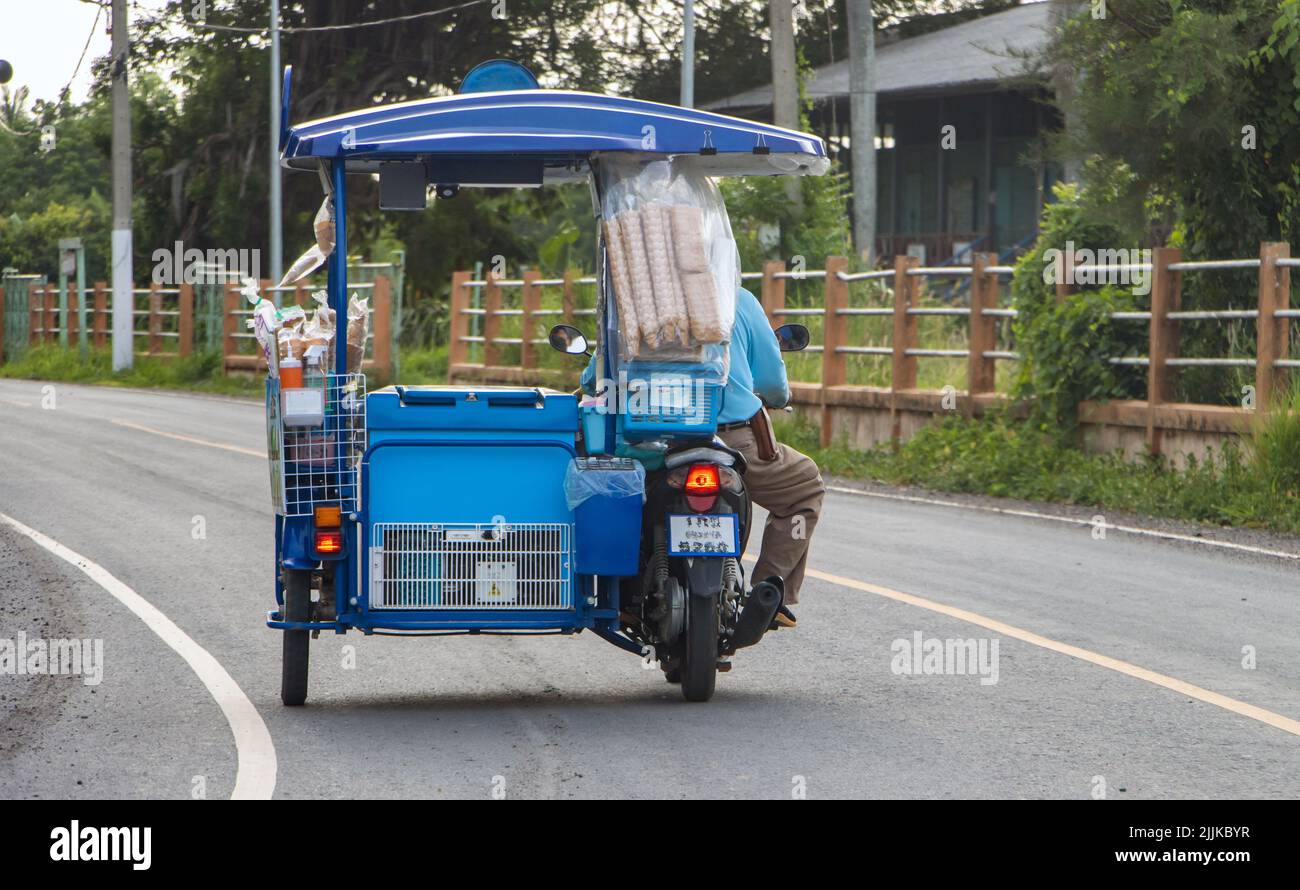 A man drives a motorcycle with a cart for the sale ice cream, rear view ...