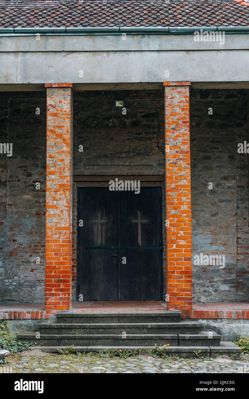 A vertical shot of a brick building with two columns at the entrance ...