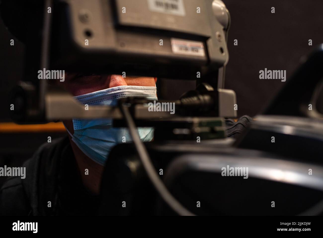 Selective focus of a cameraman holding the camera with a mask on, while ...