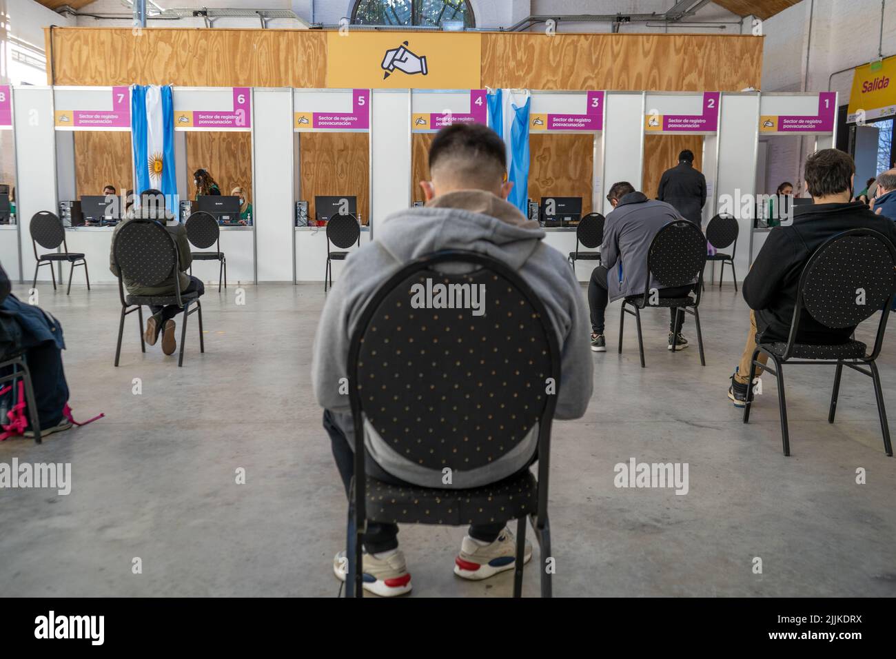 Wide shot of a waiting room, with people seated maintaining social ...