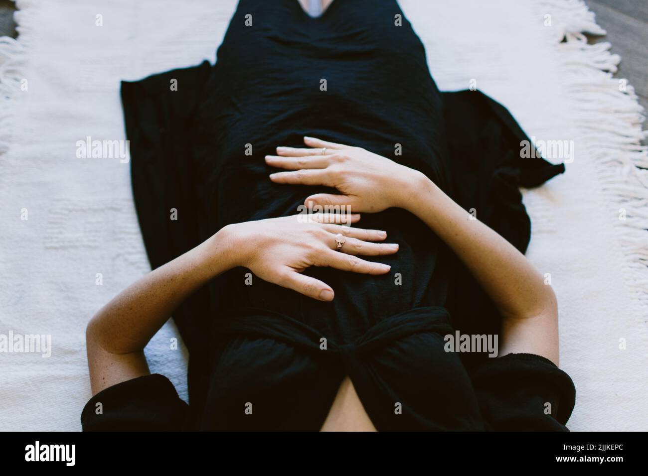 A woman with her hand on her chest and tummy lying on a carpet Stock ...