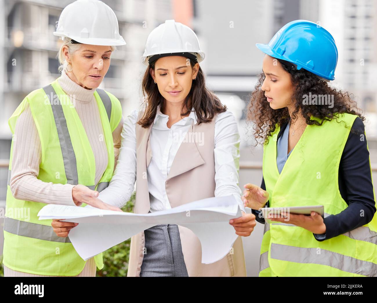 Looking over the plans. three attractive female engineers looking at ...
