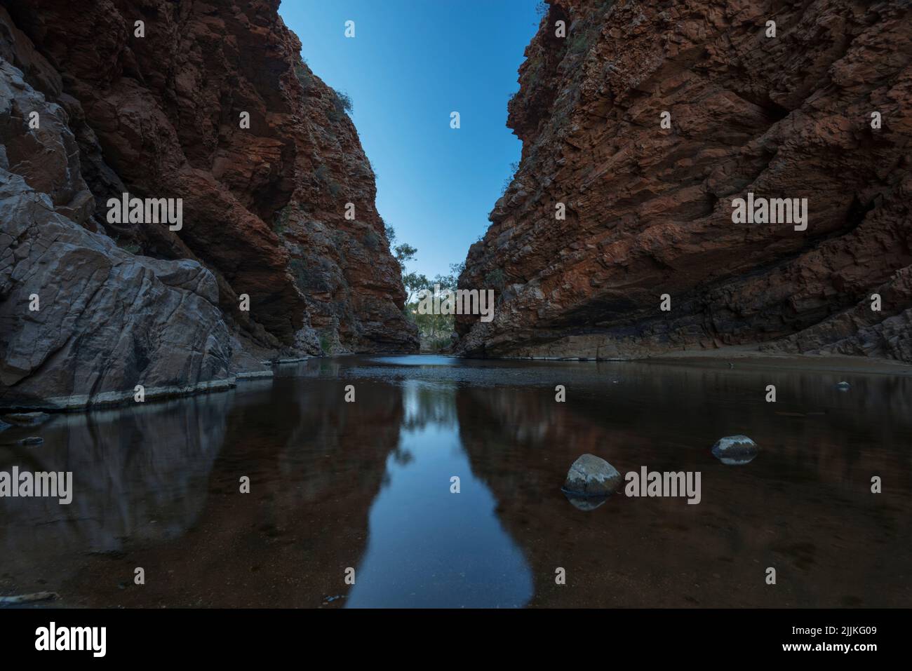 A perspective shot of a river reflecting some cliffs in the daytime ...
