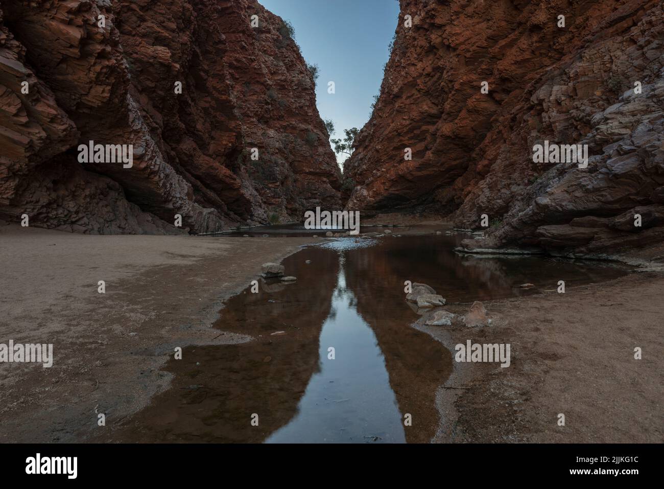 A perspective shot of a river reflecting some cliffs in the daytime ...